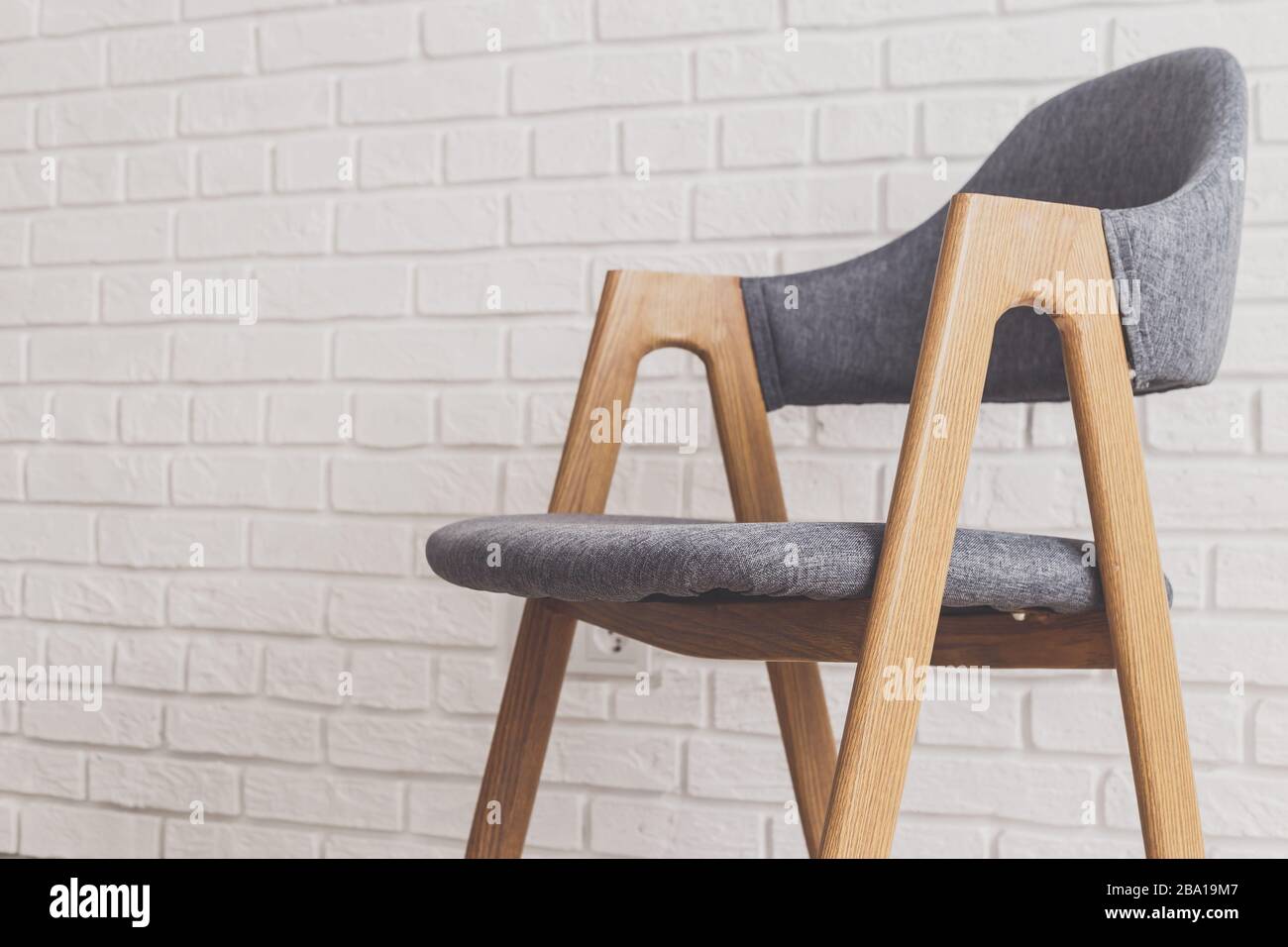 Modern grey chair with white brick walls on background Stock Photo - Alamy