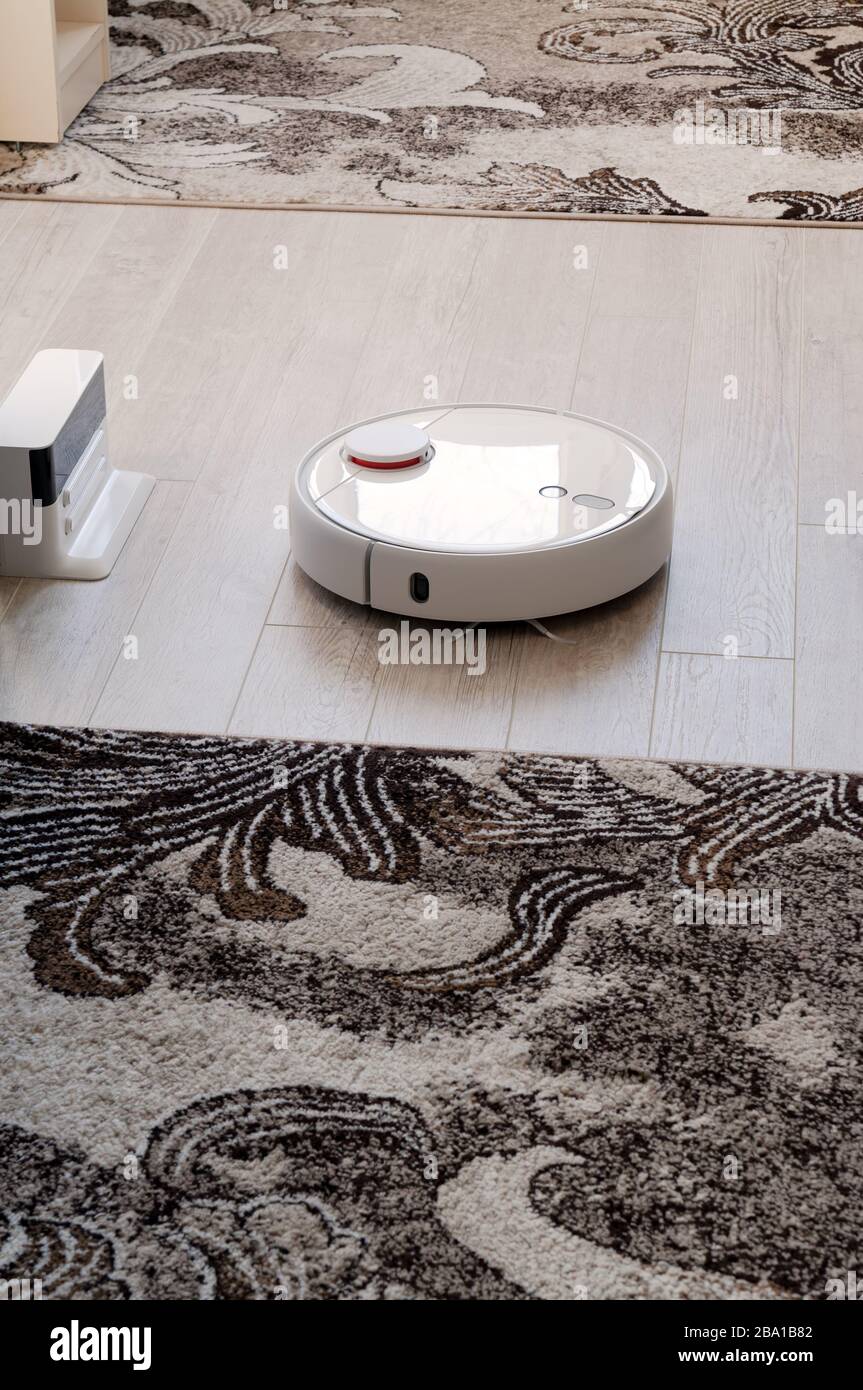 White round roboticobotic vacuum cleaner on laminate - technology ...