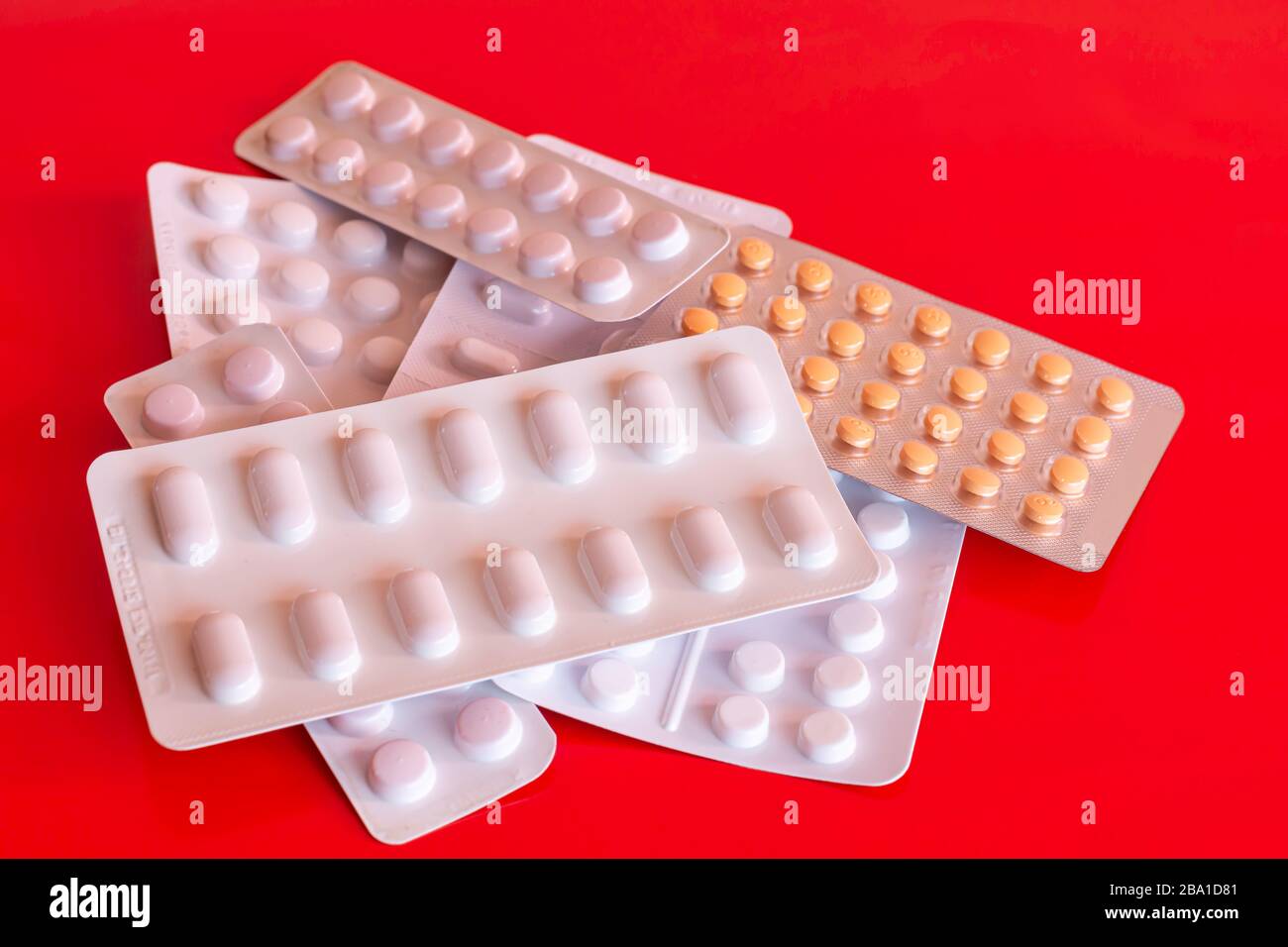 Pile of generic pills blisters on red background.No people and copy ...