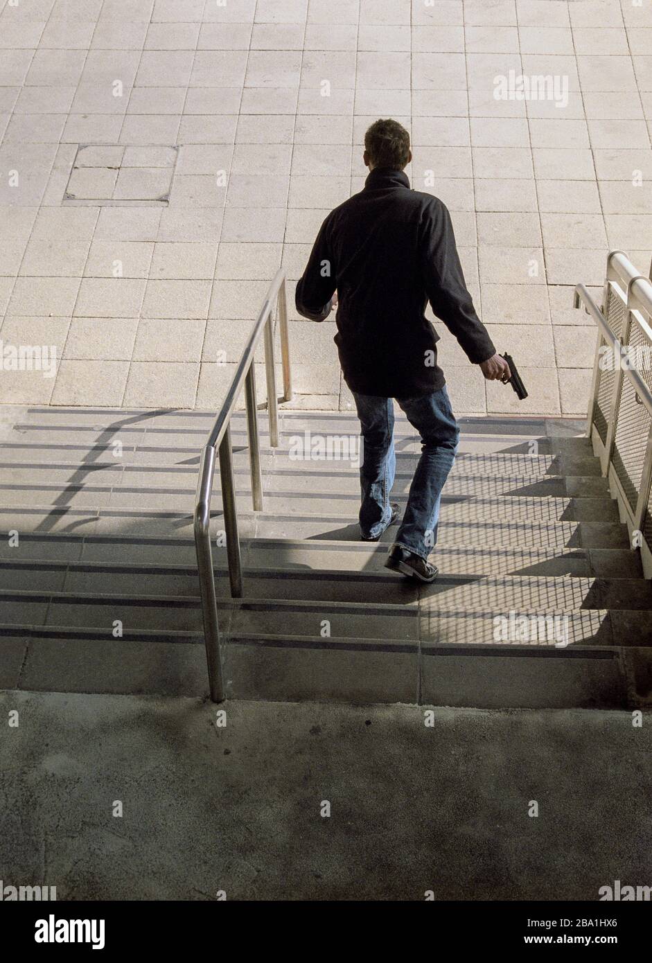 Rear View of Man with Gun walking down Steps Stock Photo - Alamy