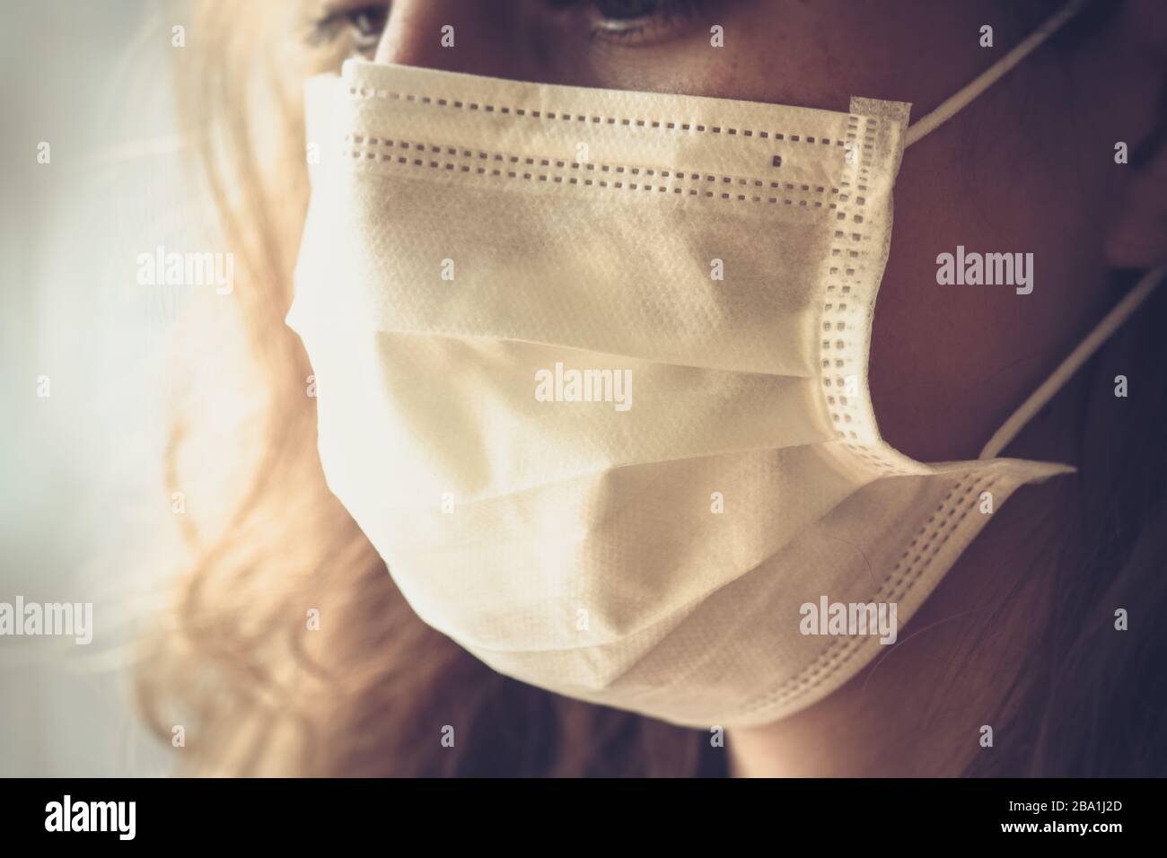 Detail of Caucasian woman wearing a white medical face mask. Sad tired ...