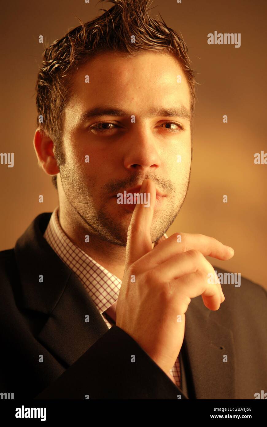 A man with a finger over his mouth Stock Photo - Alamy