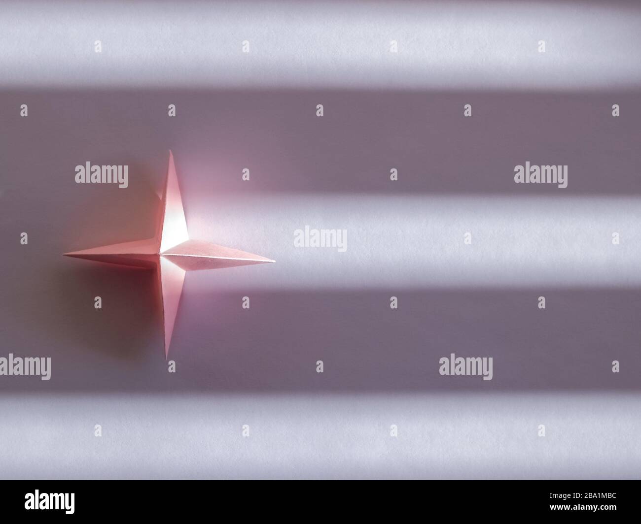 Flat lay. A four-beam peach-colored paper star lies in horizontal ...