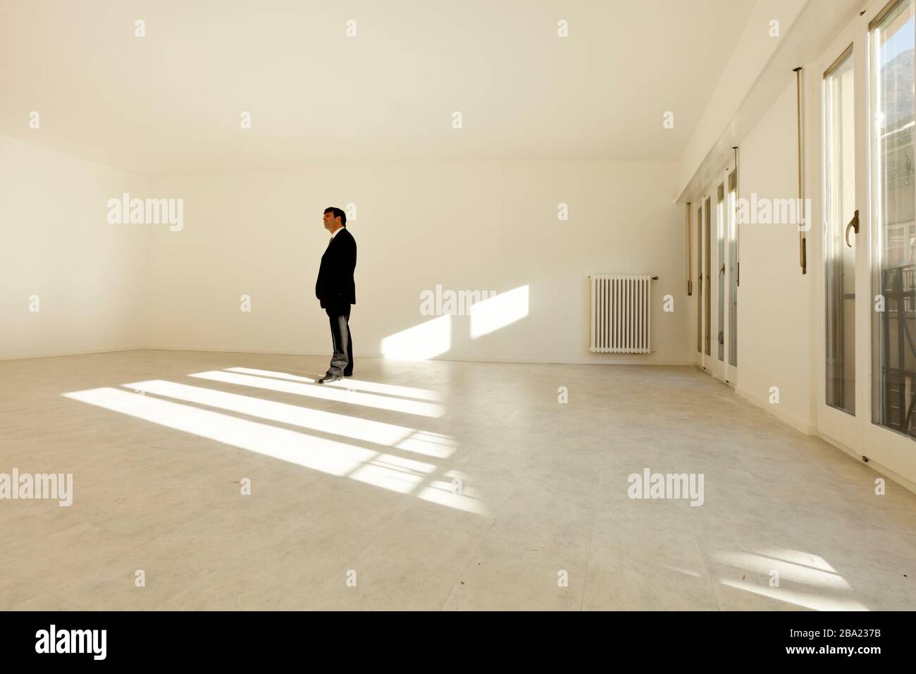 Large empty room and inside a man standing alone, waiting and thinking ...