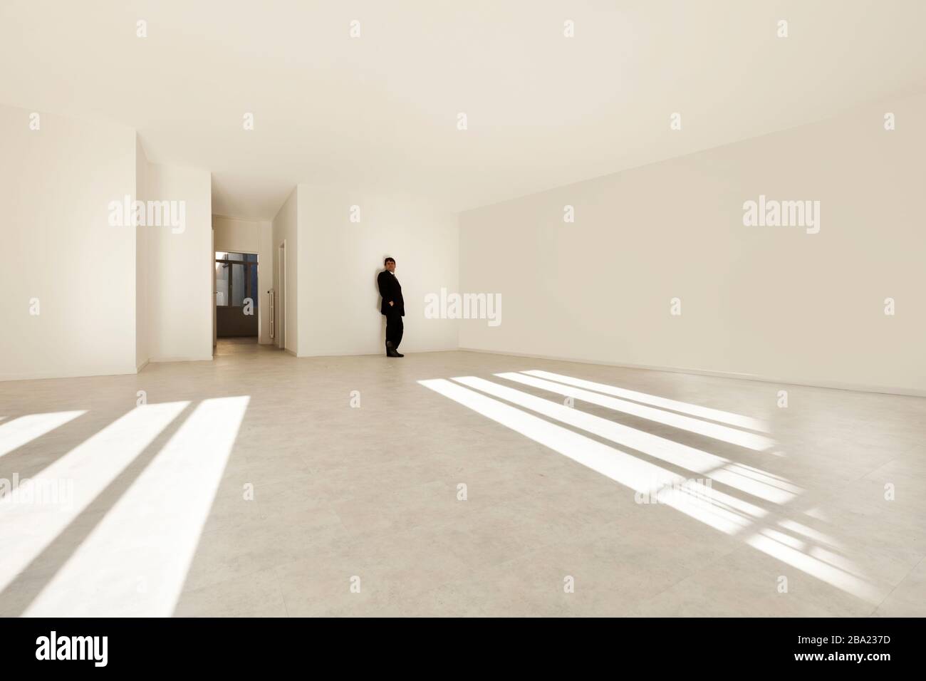 Large empty room and inside a man standing alone, waiting and thinking ...