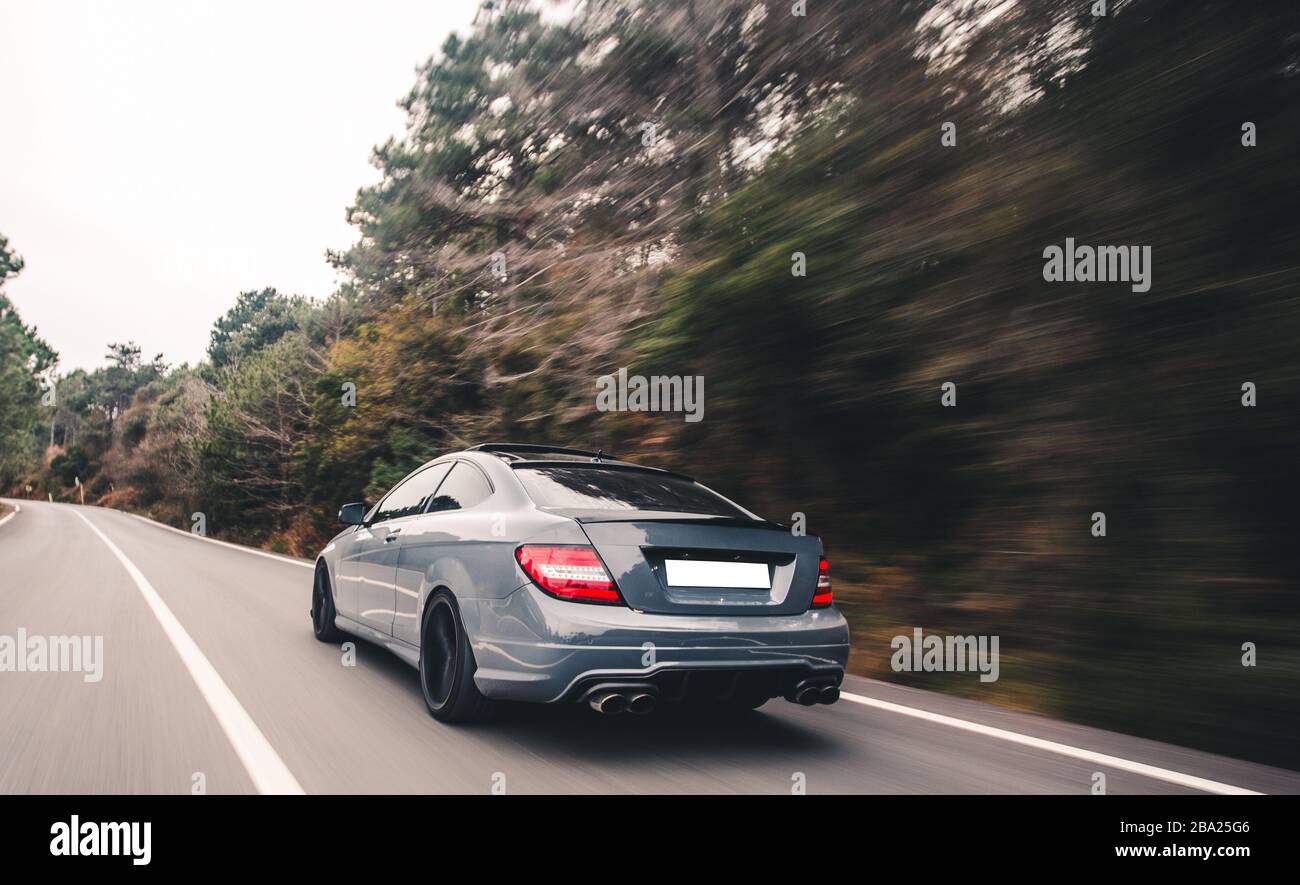 Grey business class coupe sedan driving on the road. Backside view ...