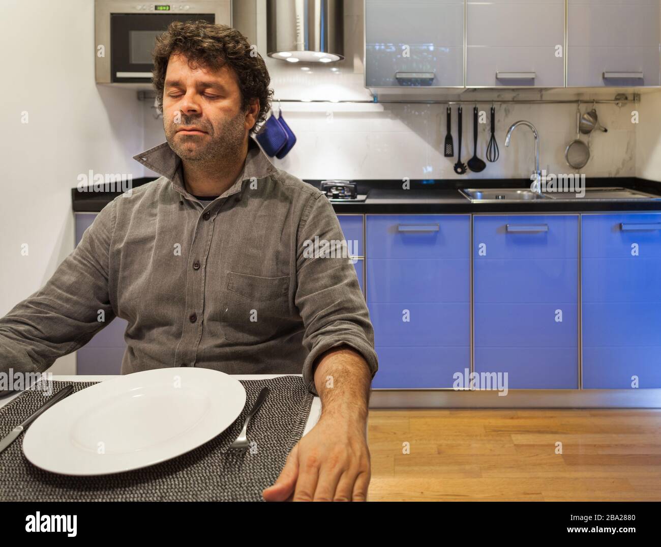 portrait of man sitting on the table of kitchen Stock Photo - Alamy