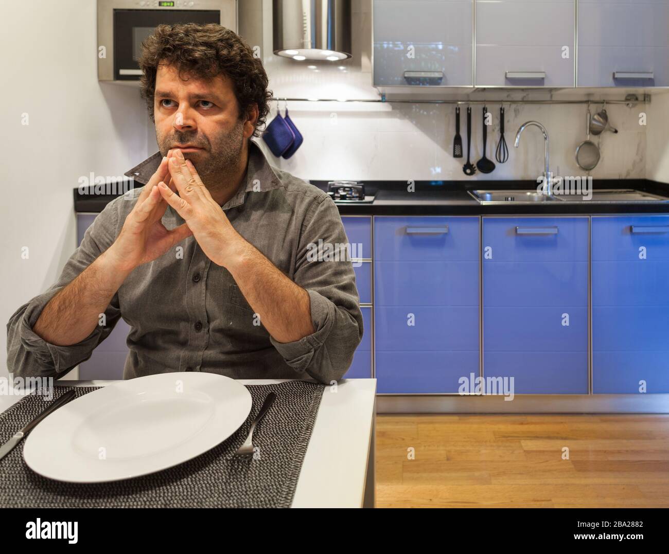 portrait of man sitting on the table of kitchen Stock Photo - Alamy