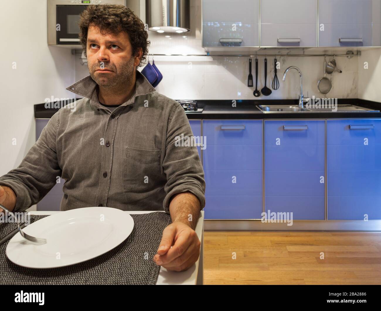 portrait of man sitting on the table of kitchen Stock Photo - Alamy