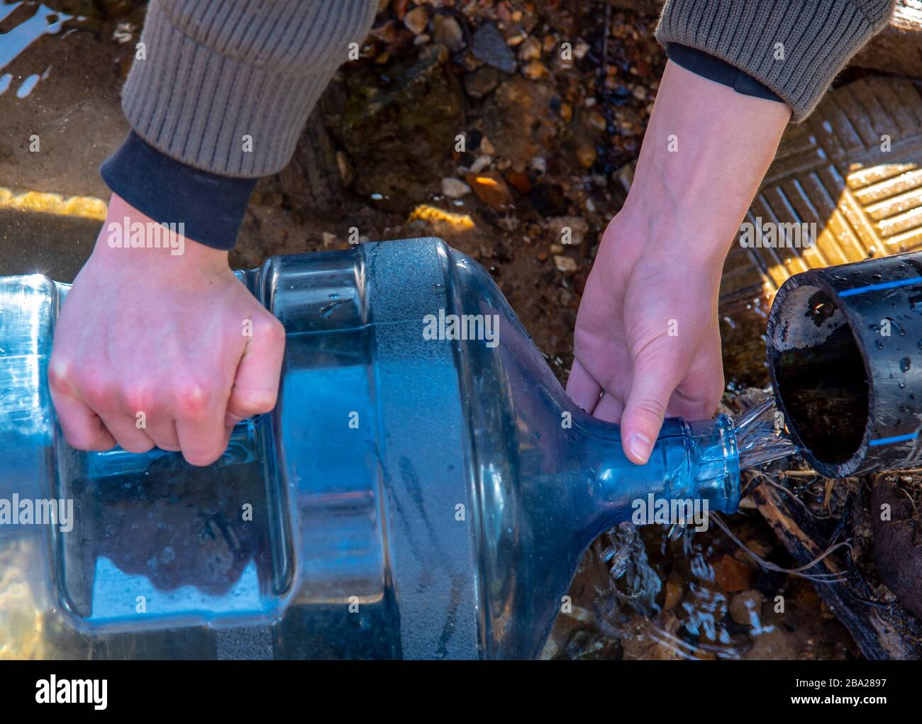 Men's hands fill a plastic bottle with water from a spring Stock Photo ...