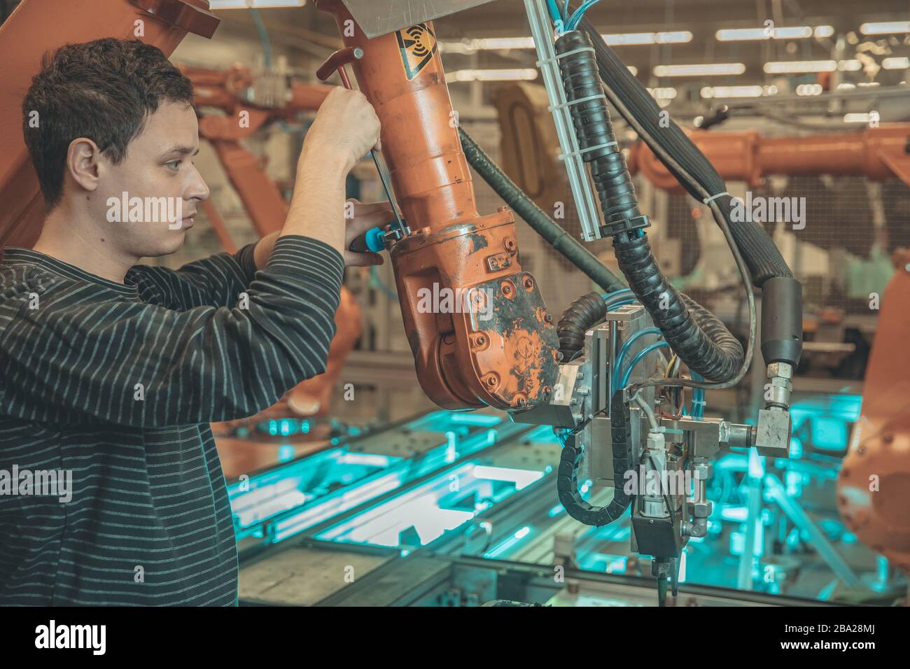 Technical worker performs maintenance robotic arms on the production ...