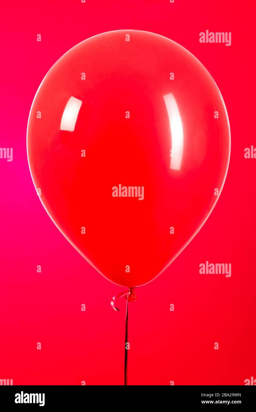 One red ball isolated on a red background, birthday decoration ...