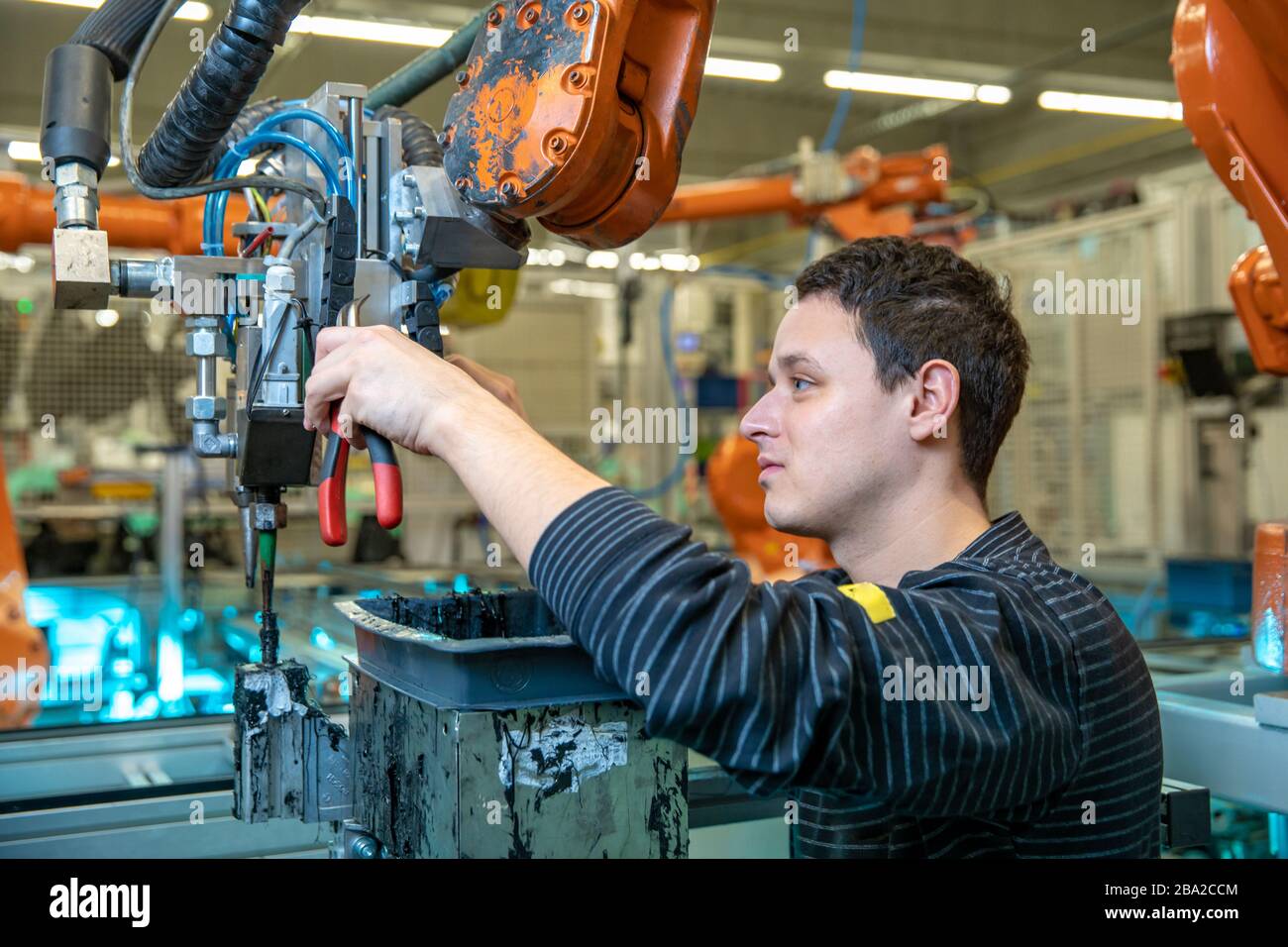 Technical worker performs maintenance robotic arms on the production ...