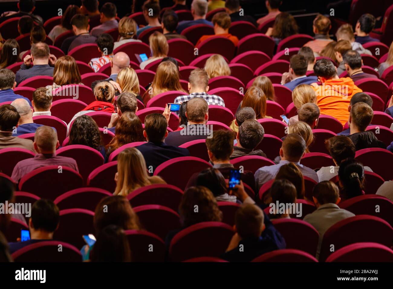 Business conference attendees sit and listen to lecturer, rear view ...