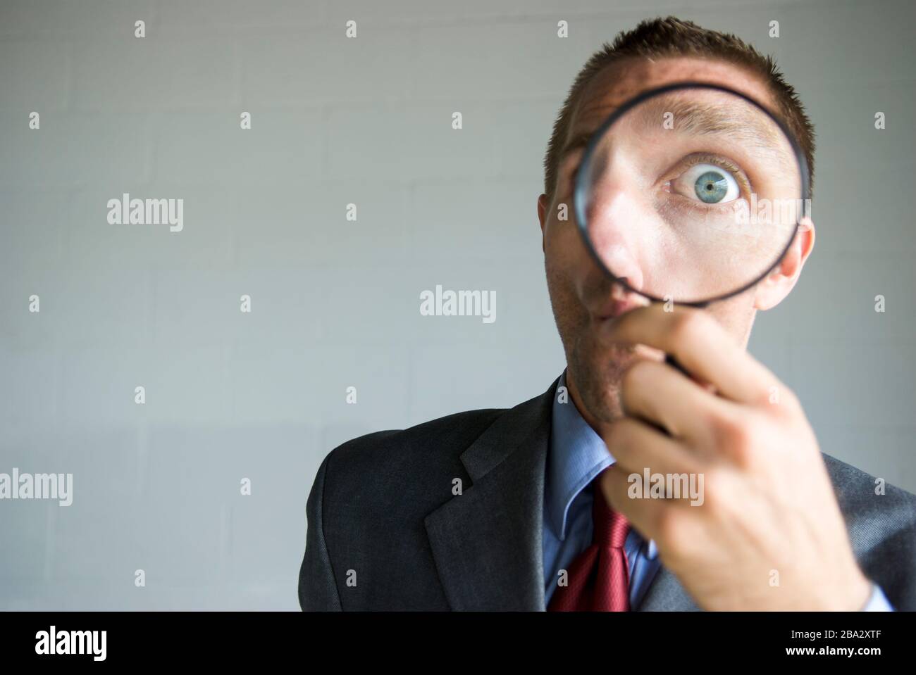 Surprised businessman searching with enlarged eye looking through ...