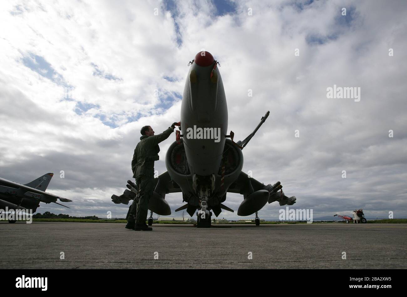 Flight Lieutenant Andy Chisholm, checks over his Harrier before the ...