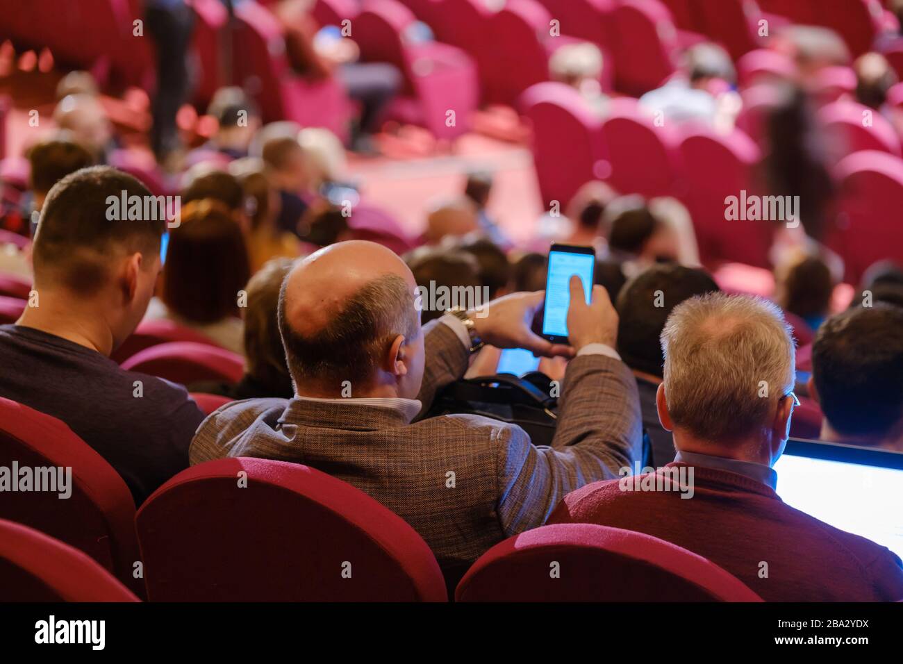 Business conference attendees sit and listen to lecturer, rear view ...