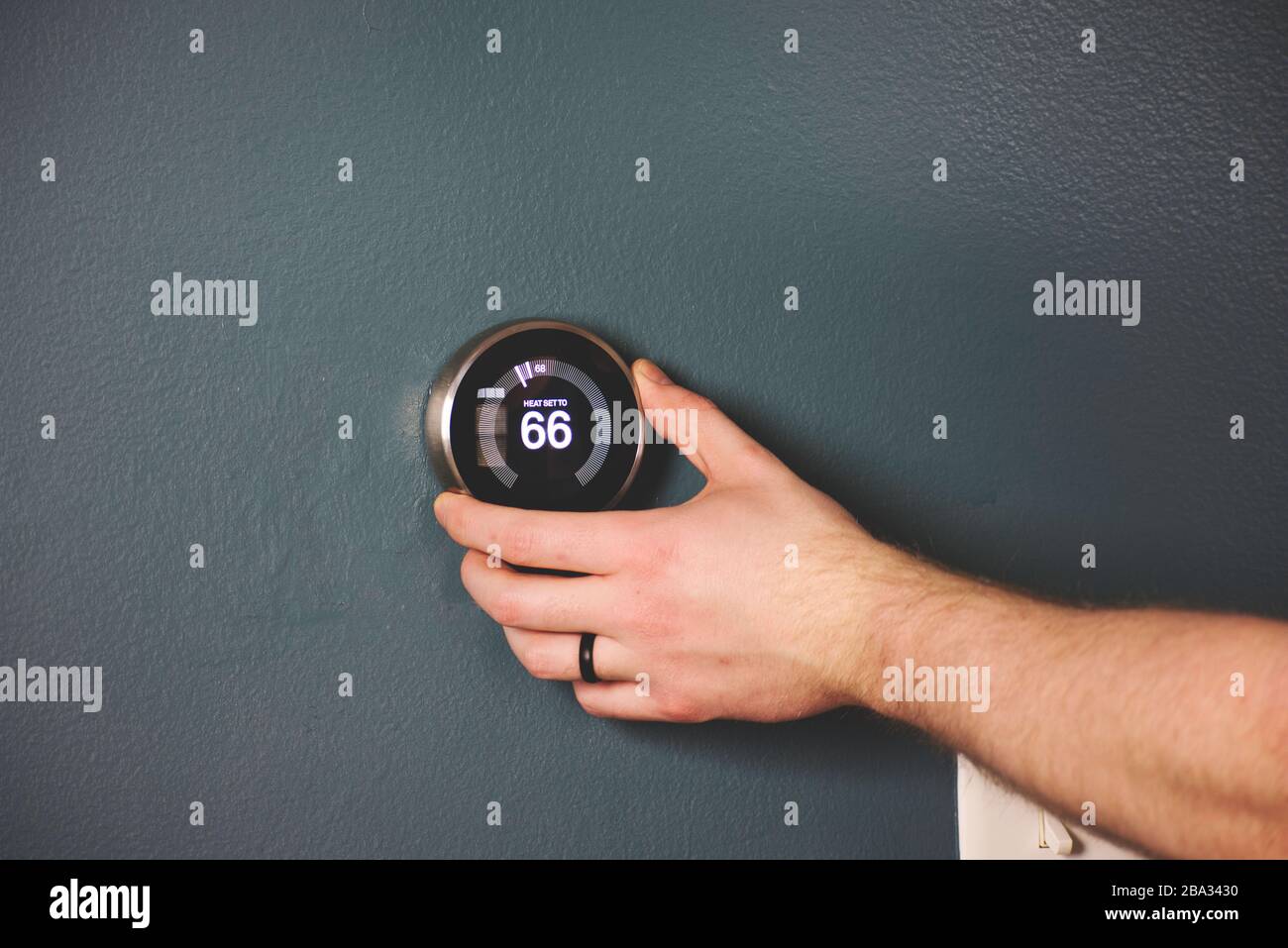 Hand adjusting temperature on electric thermostat Stock Photo - Alamy