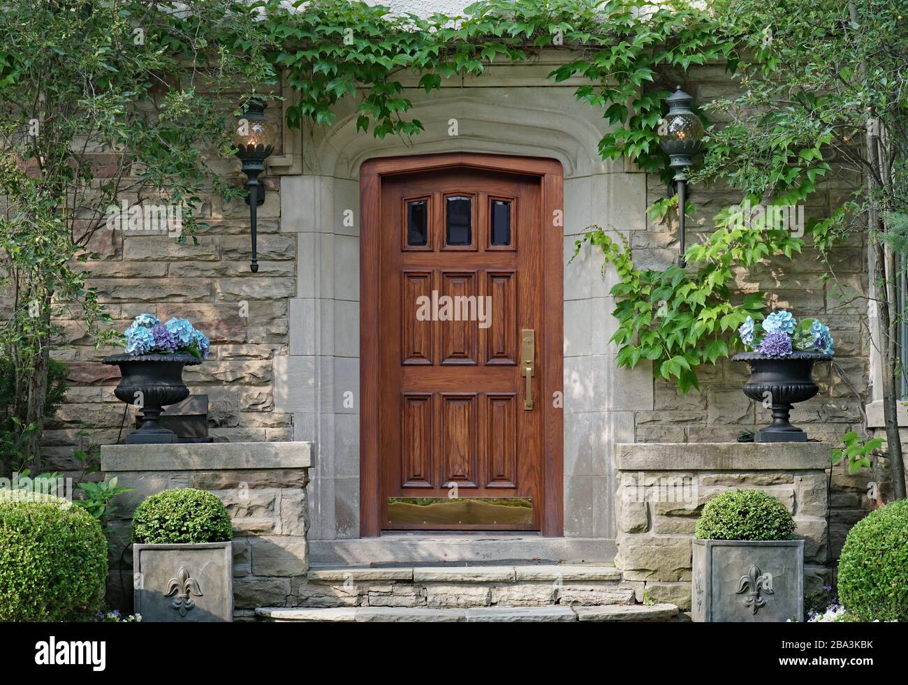 elegant wooden front door of stone house with flower pots and vines ...