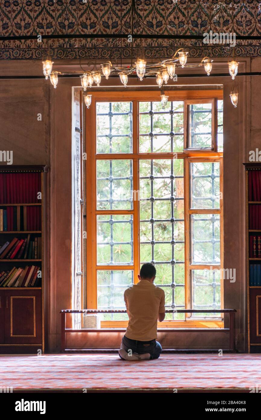 Believer man praying in front of a large window in a mosque, portrait ...