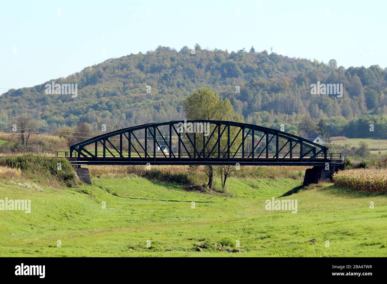 Dark green strong steel railway arch bridge mounted on concrete ...