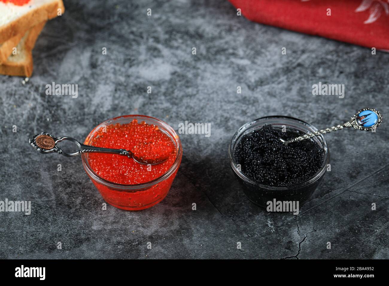 Black and red caviar, seafood in a small jars with a spoon inside on a ...