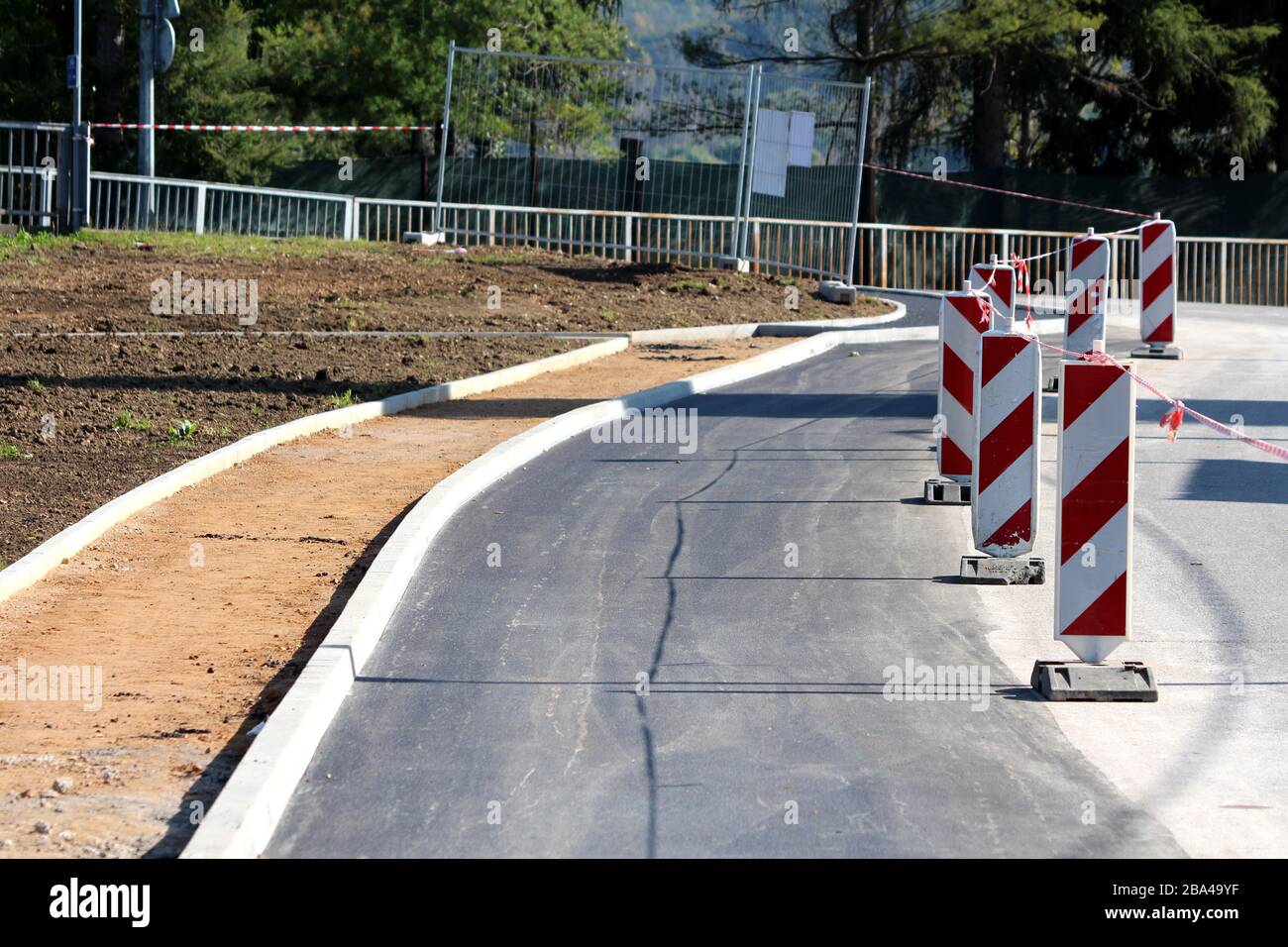 Freshly paved road still under construction filled with stripped red ...