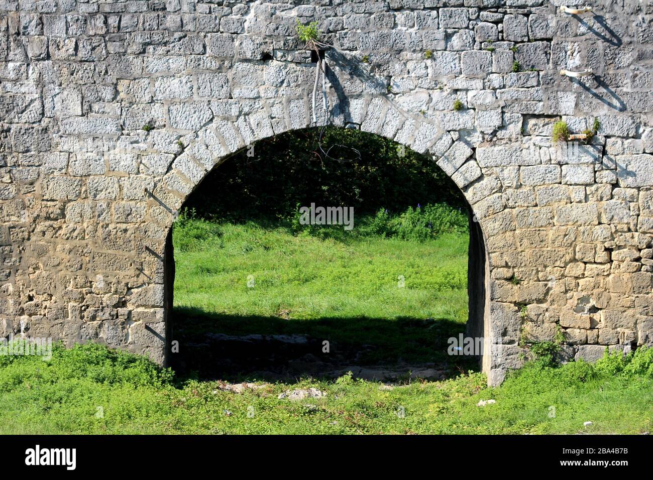 Front view of massive old stone arch with wires hanging on top under ...