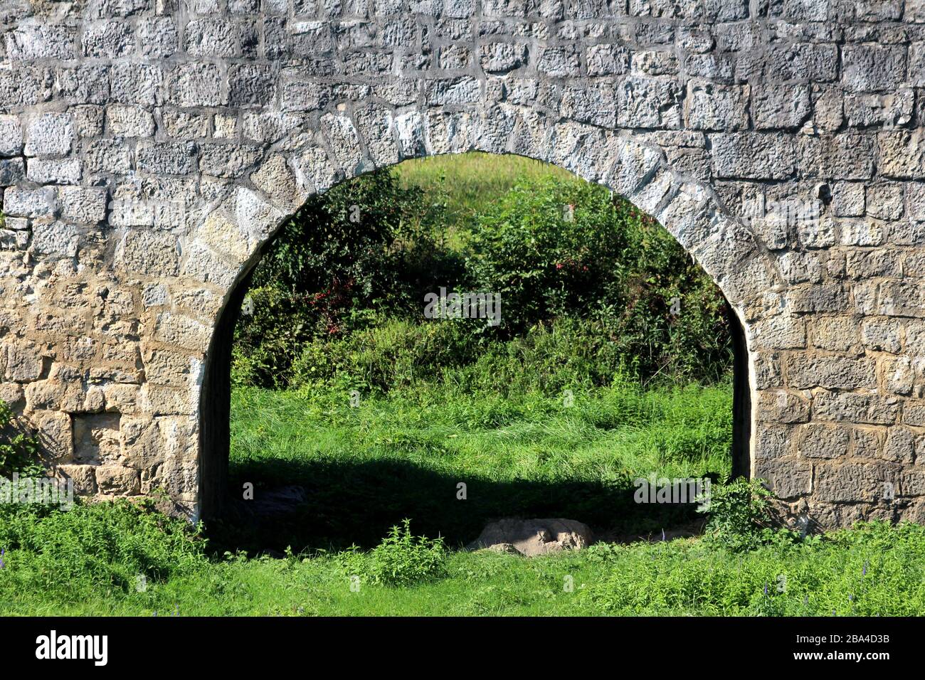 Massive old stone arch under stone bridge allowing access to local ...