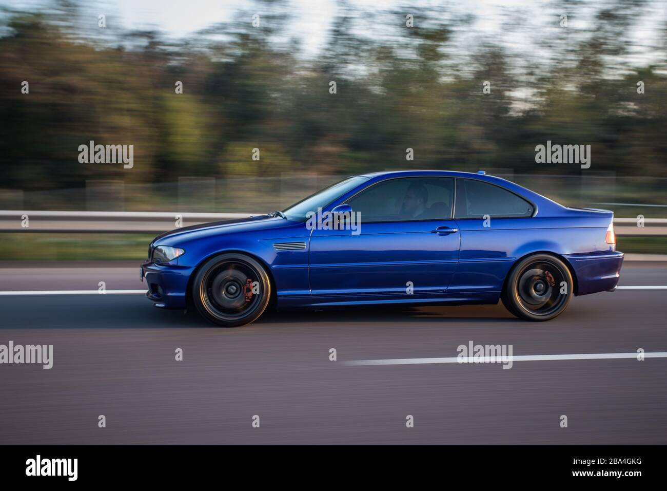 Blue sedan car on the forest road Stock Photo - Alamy