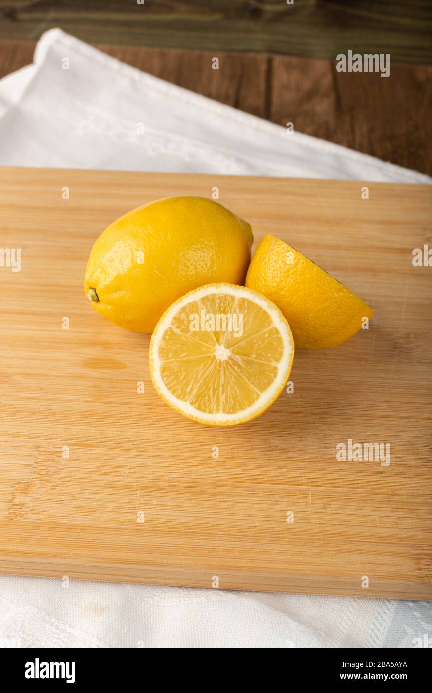 Half cut and whole lemon pieces on a wooden board Stock Photo - Alamy