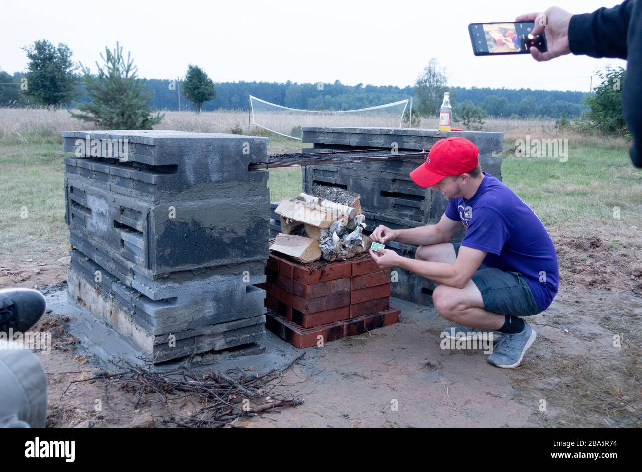 Young man lighting a fire in the new outdoor fireplace that he helped ...