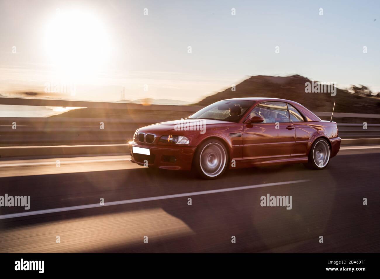 Red sedan car driving under the sunlight Stock Photo - Alamy