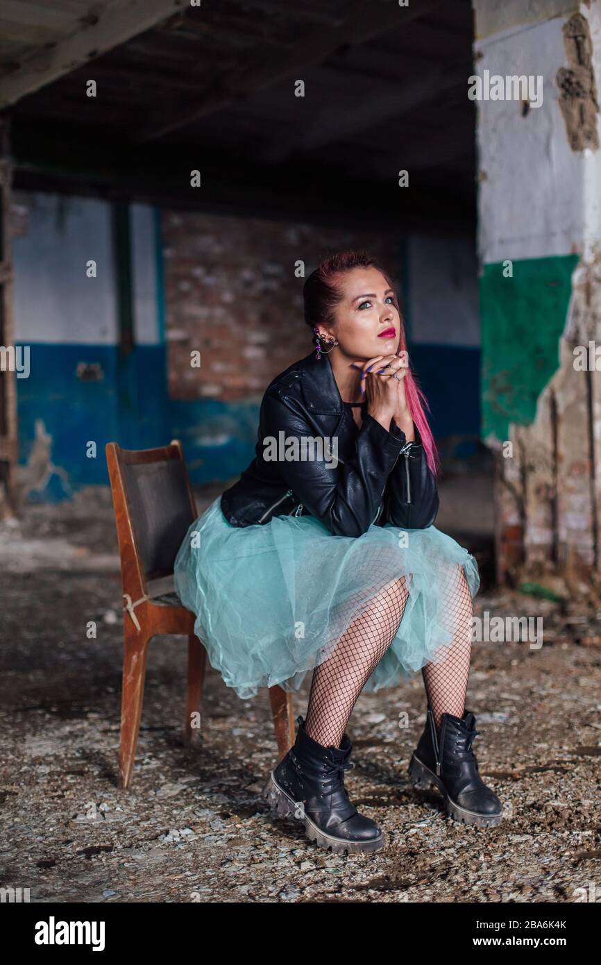 Portrait of a young girl with pink hair sitting old the old chair ...