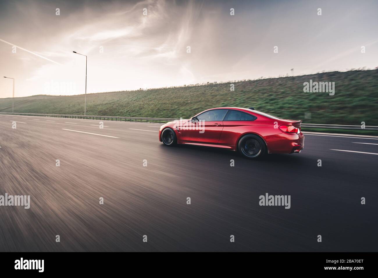 Red luxury sedan driving in the dusk time Stock Photo - Alamy