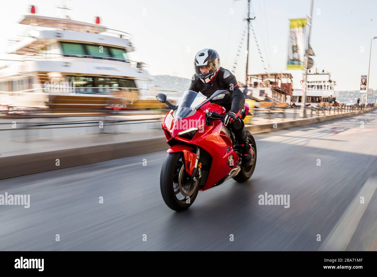 Biker driving a red motorcycle at the sea port Stock Photo - Alamy