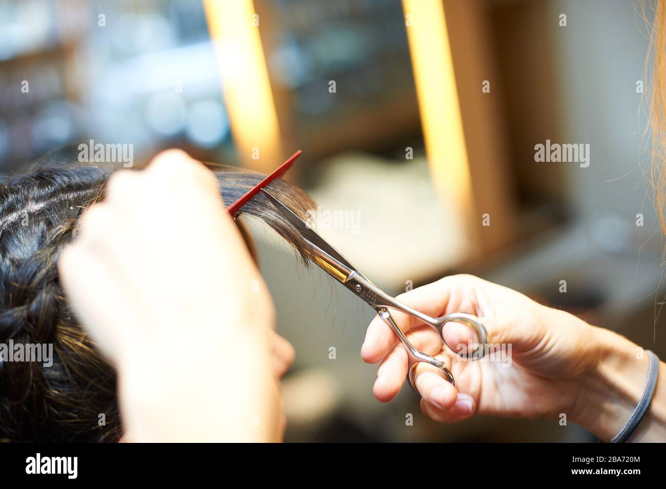 Close up photograph of hands cutting hair with scissors at a salon ...