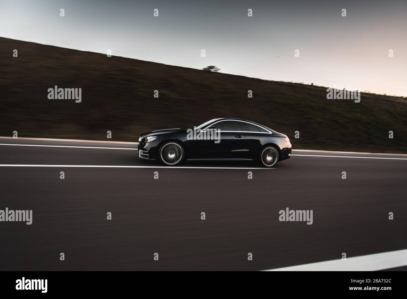 Black business class sedan driving across hills Stock Photo - Alamy