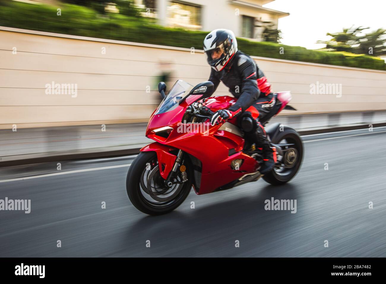Biker driving a red motorcycle in helmet and gear Stock Photo - Alamy