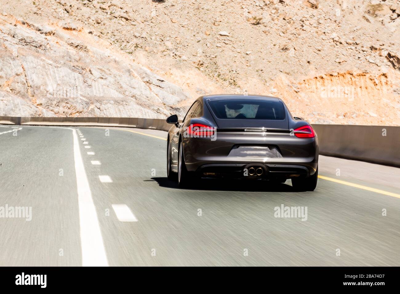 Driving a grey color sport car through the mountains under the sun ...
