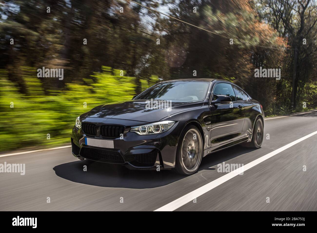 Grey luxury sport car driving across green trees Stock Photo - Alamy