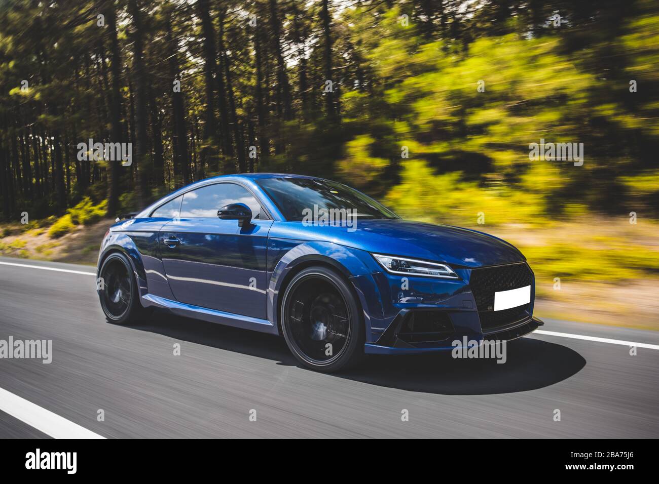 Blue luxury sedan coupe car on the highway in the forest Stock Photo ...