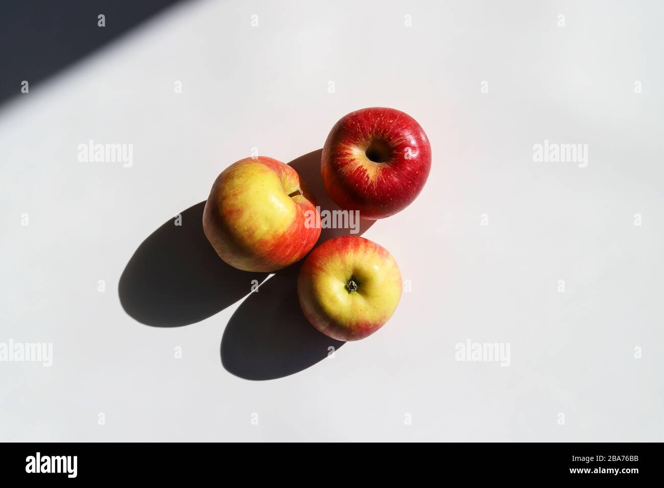 Fresh apples with strong shadow on white background at sunny day ...