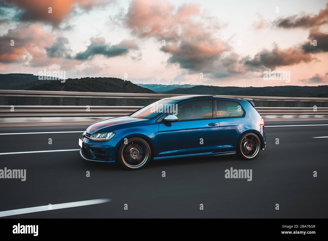 Blue car on the road in a cloudy weather Stock Photo - Alamy