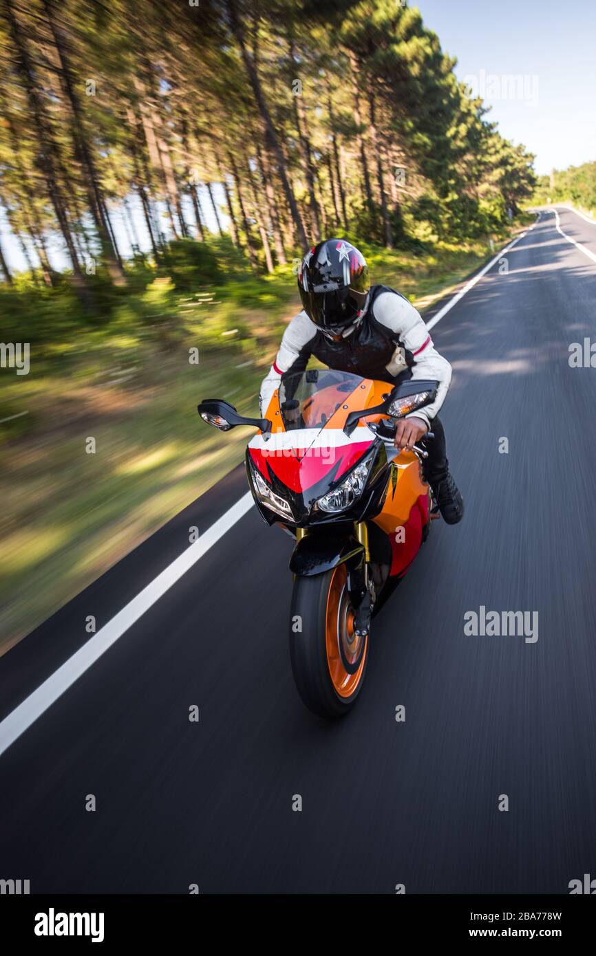 Orange color motorcycle with a driver in helmet Stock Photo - Alamy