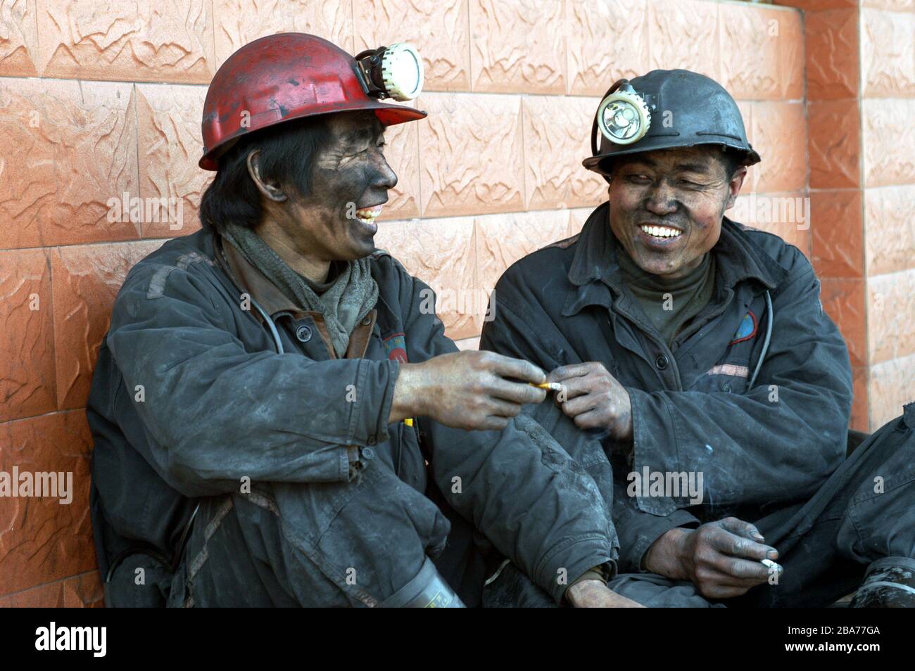 Chinese coal miners, who have just left work underground, smoke ...