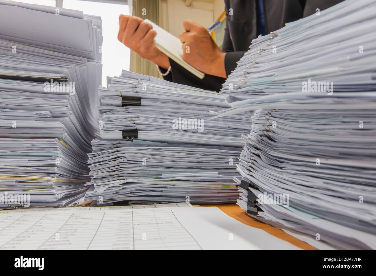 documents on desk stack up high waiting to be managed Stock Photo - Alamy