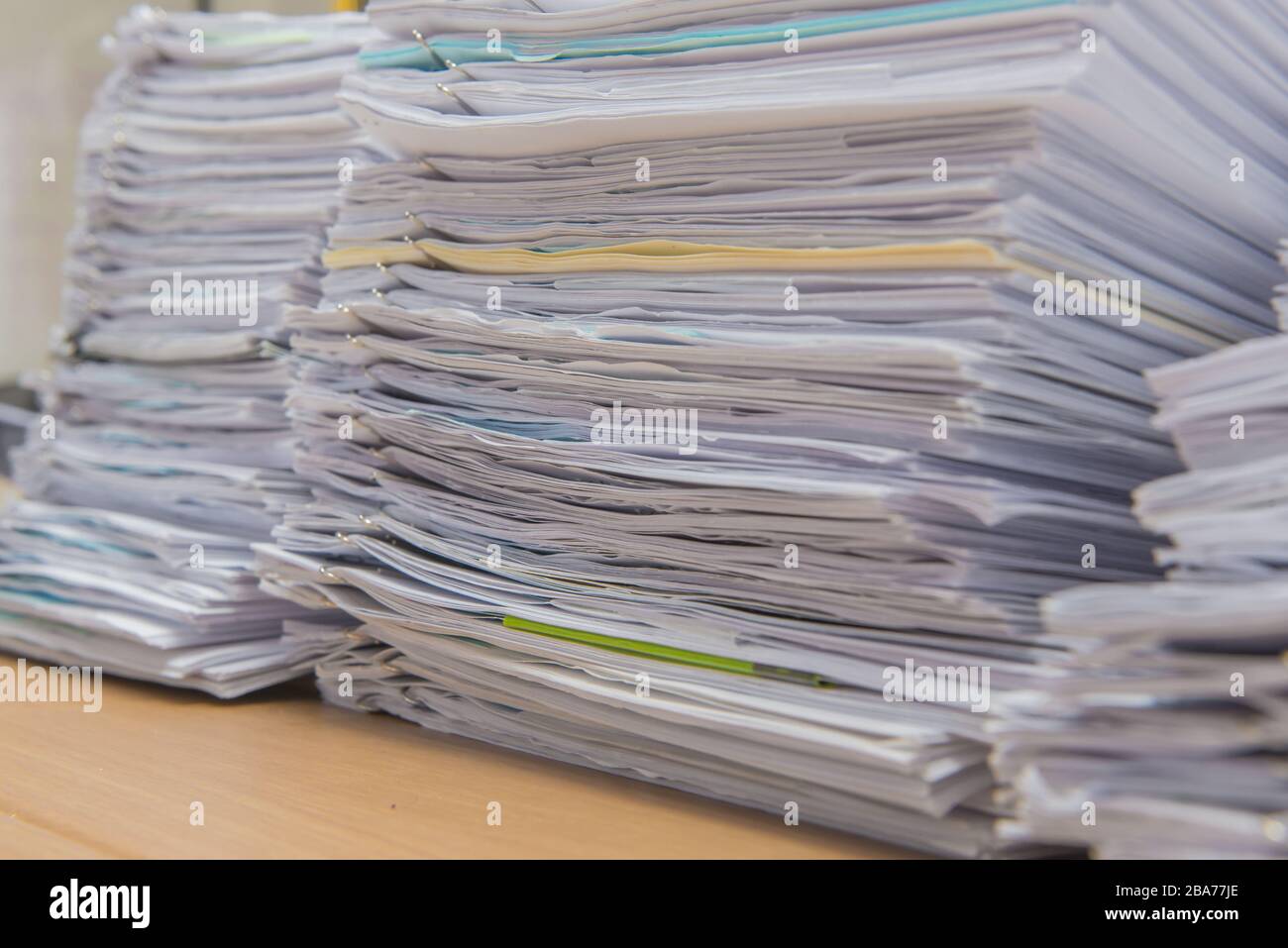 documents on desk stack up high waiting to be managed Stock Photo - Alamy