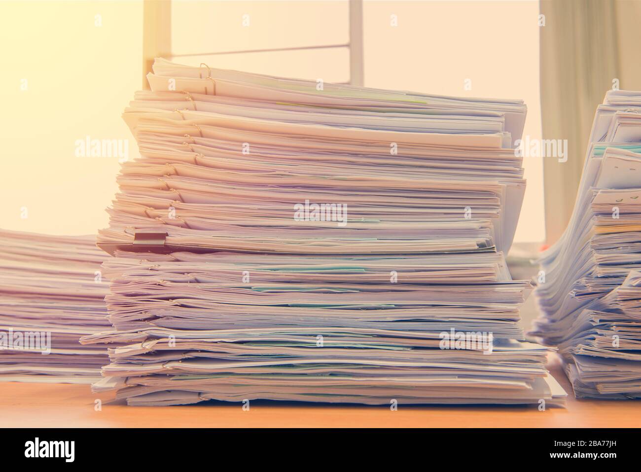documents on desk stack up high waiting to be managed Stock Photo - Alamy