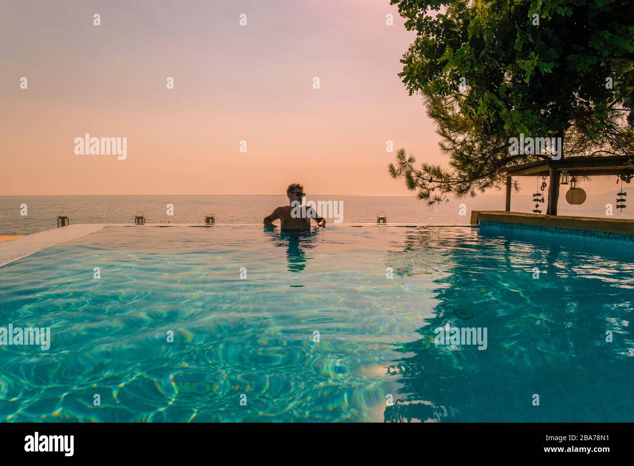 Fethiye Turkey, young guy in swim short watching sunset by the pool ...